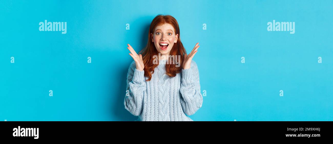 Surprised and happy redhead girl clap hands and staring at camera ...