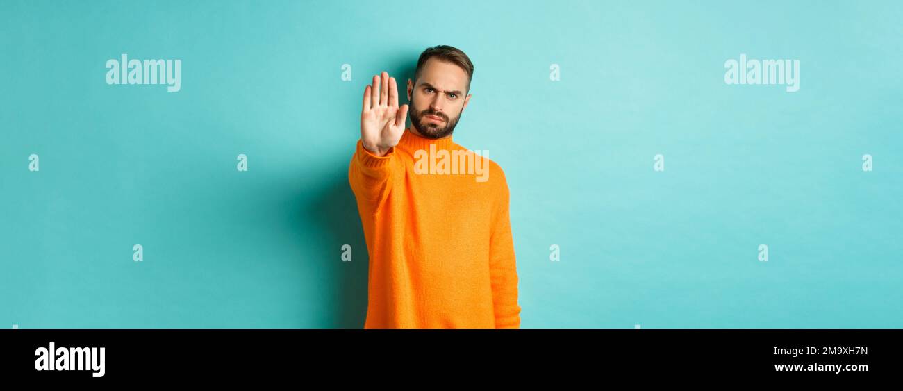 Serious frowning man showing stop gesture, telling no, prohibit and ...