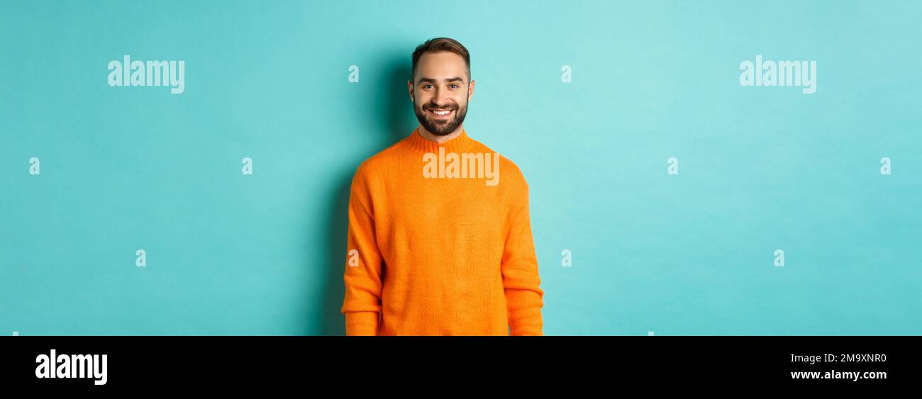 Lifestyle. Handsome man in orange sweater smiling at camera, happy face ...