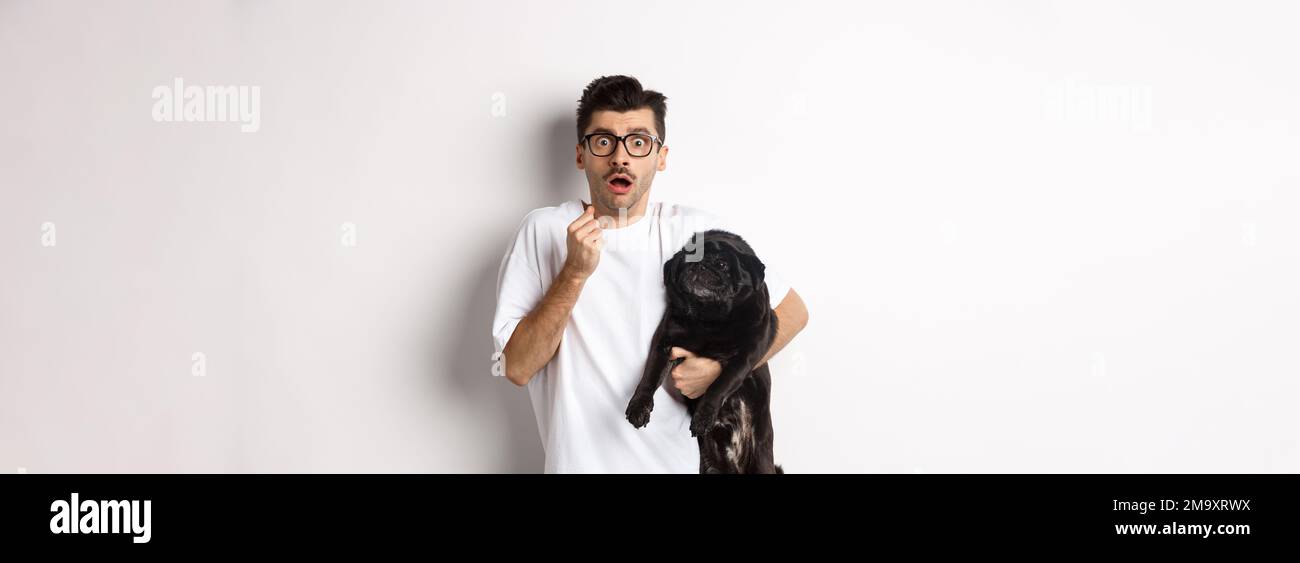 Scared hipster hugging his cute black puppy and staring at camera ...