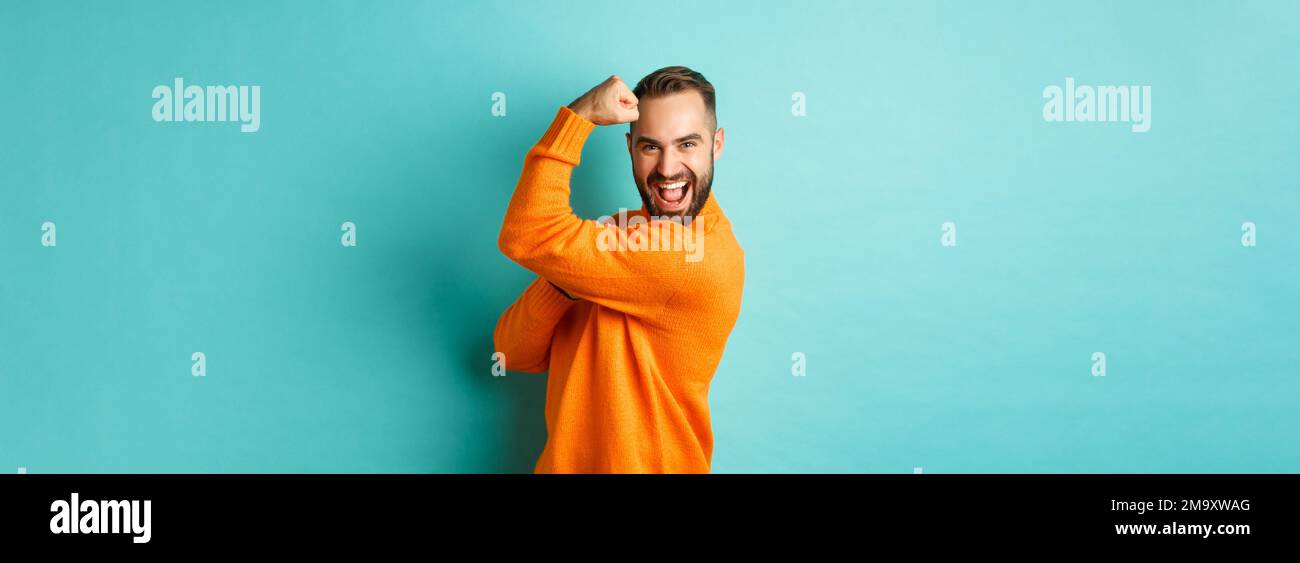 Confident handsome man show-off his muscles, flex biceps, feeling ...