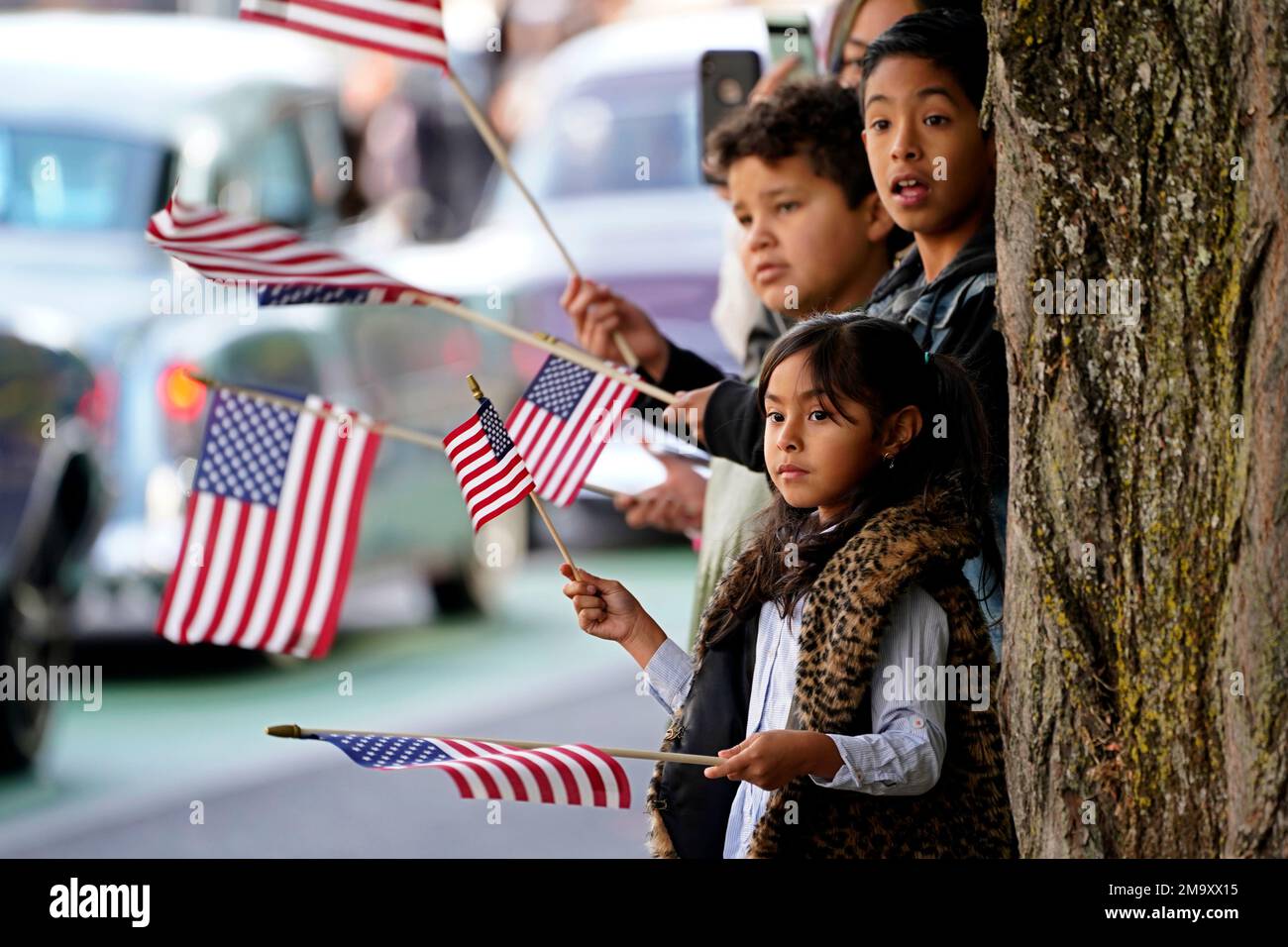 Children wave American flags as a group of classic cars passes during a ...