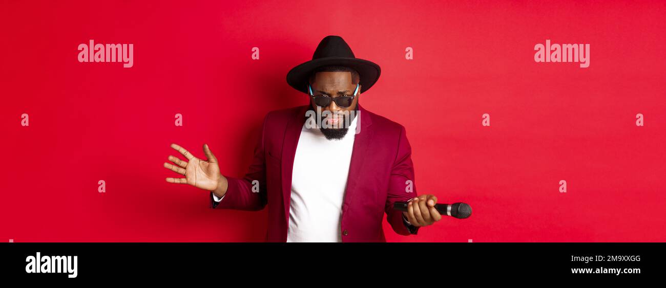 Passionate black male singer performing against red background, singing ...