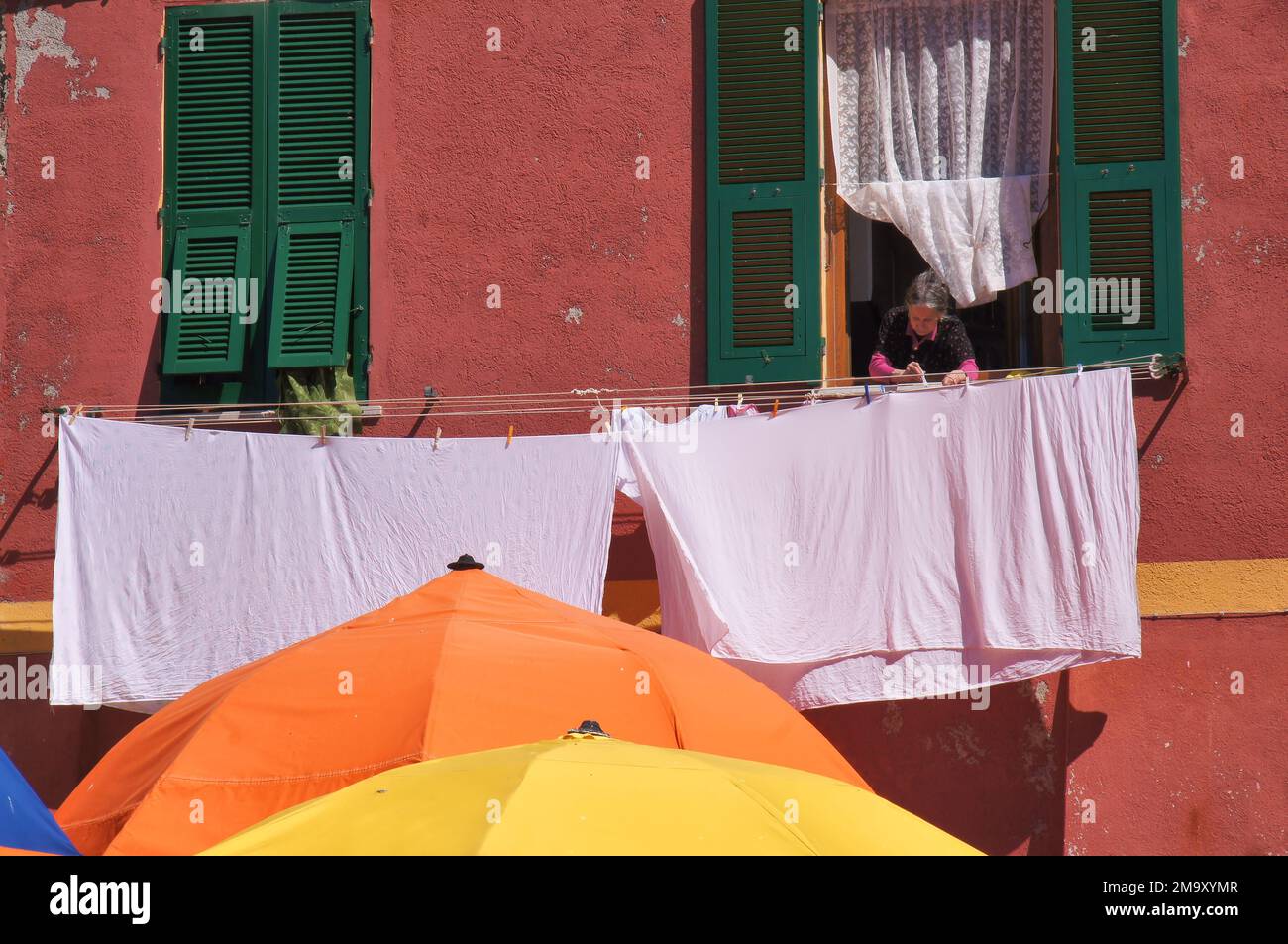Vernazza: Woman hanging out washing from window of colourful building ...