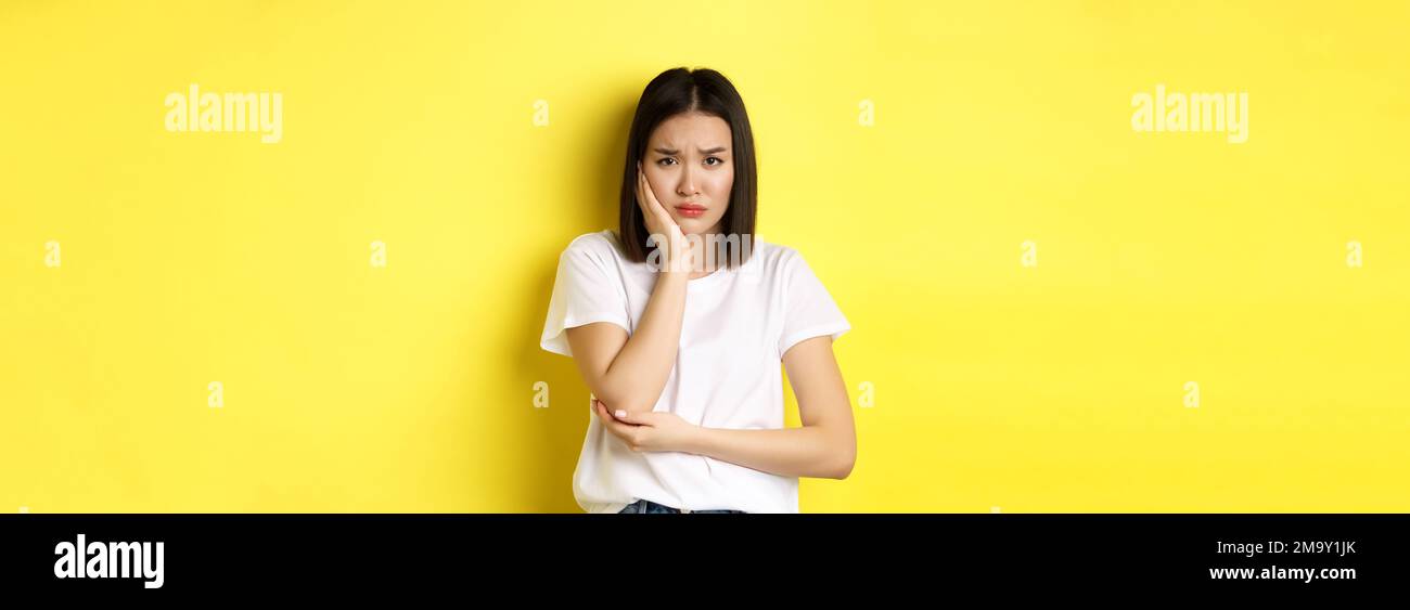 Sad asian woman touching cheek and frowning, having toothache, need see ...