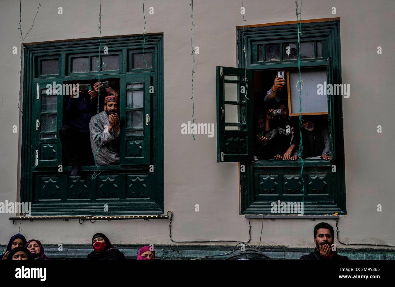 Kashmiri Muslim devotees pray from the windows of a mosque as a priest ...
