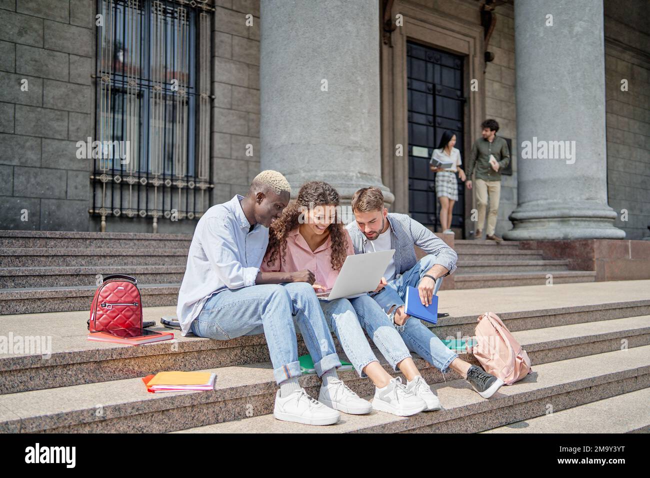 student friends discussing internet news while sitting on the steps ...