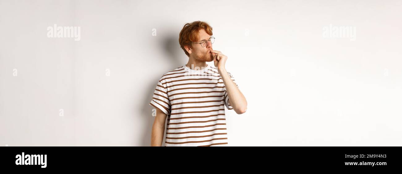Image of satisfied young man with red hair and glasses kissing fingers ...