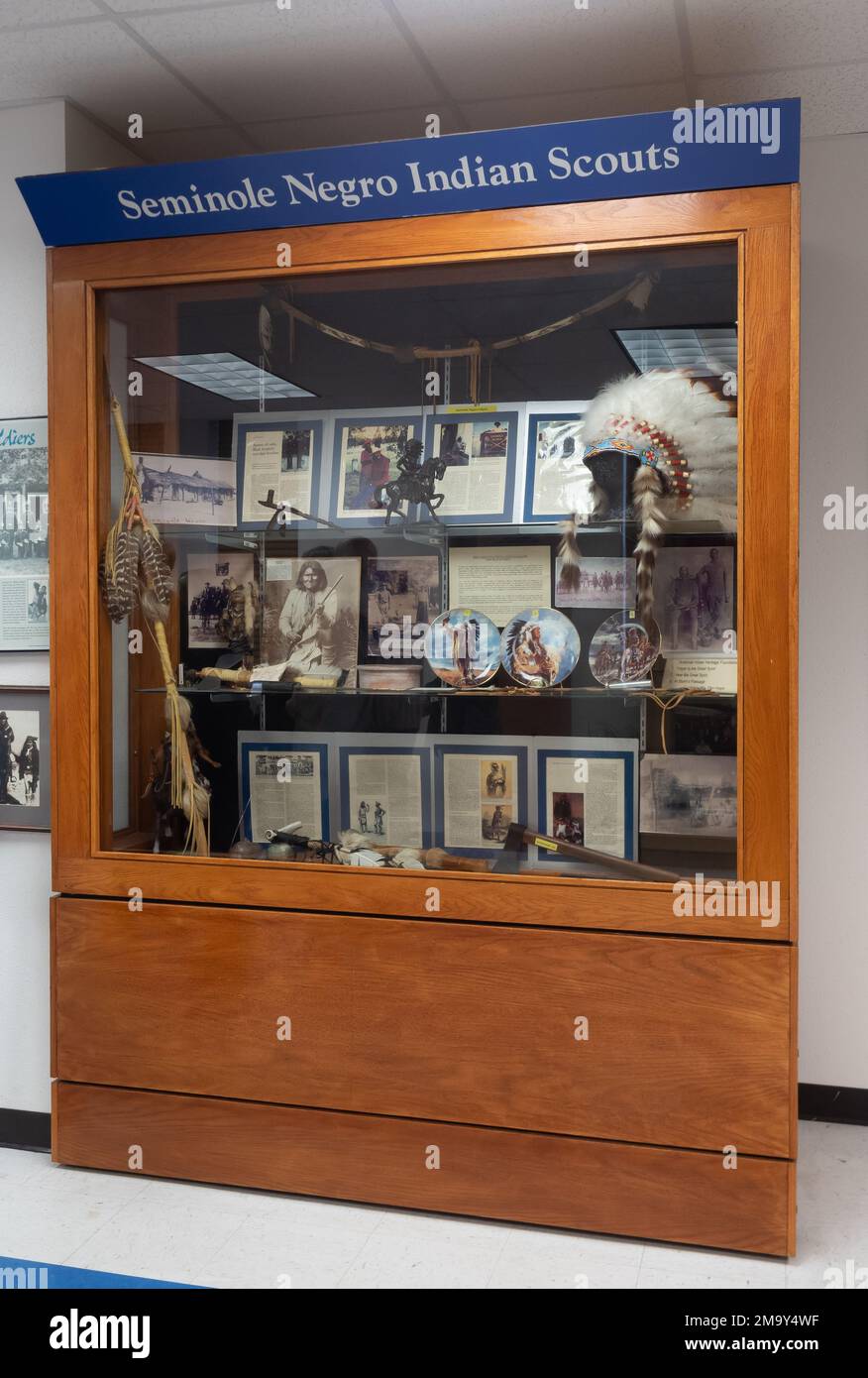 Display case with photos, a headdress, tomahawks, and educational ...