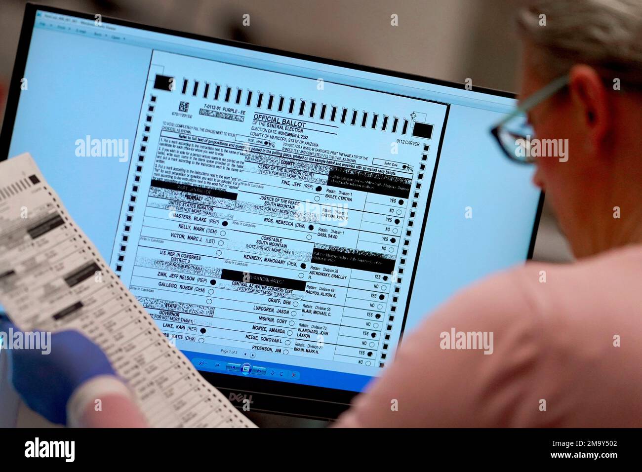 An election worker verifies a ballot on a screen inside the Maricopa ...