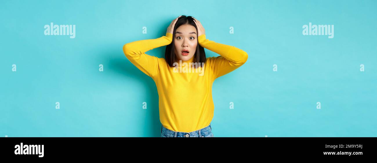 Shocked asian woman looking speechless, gasping amazed and holding ...