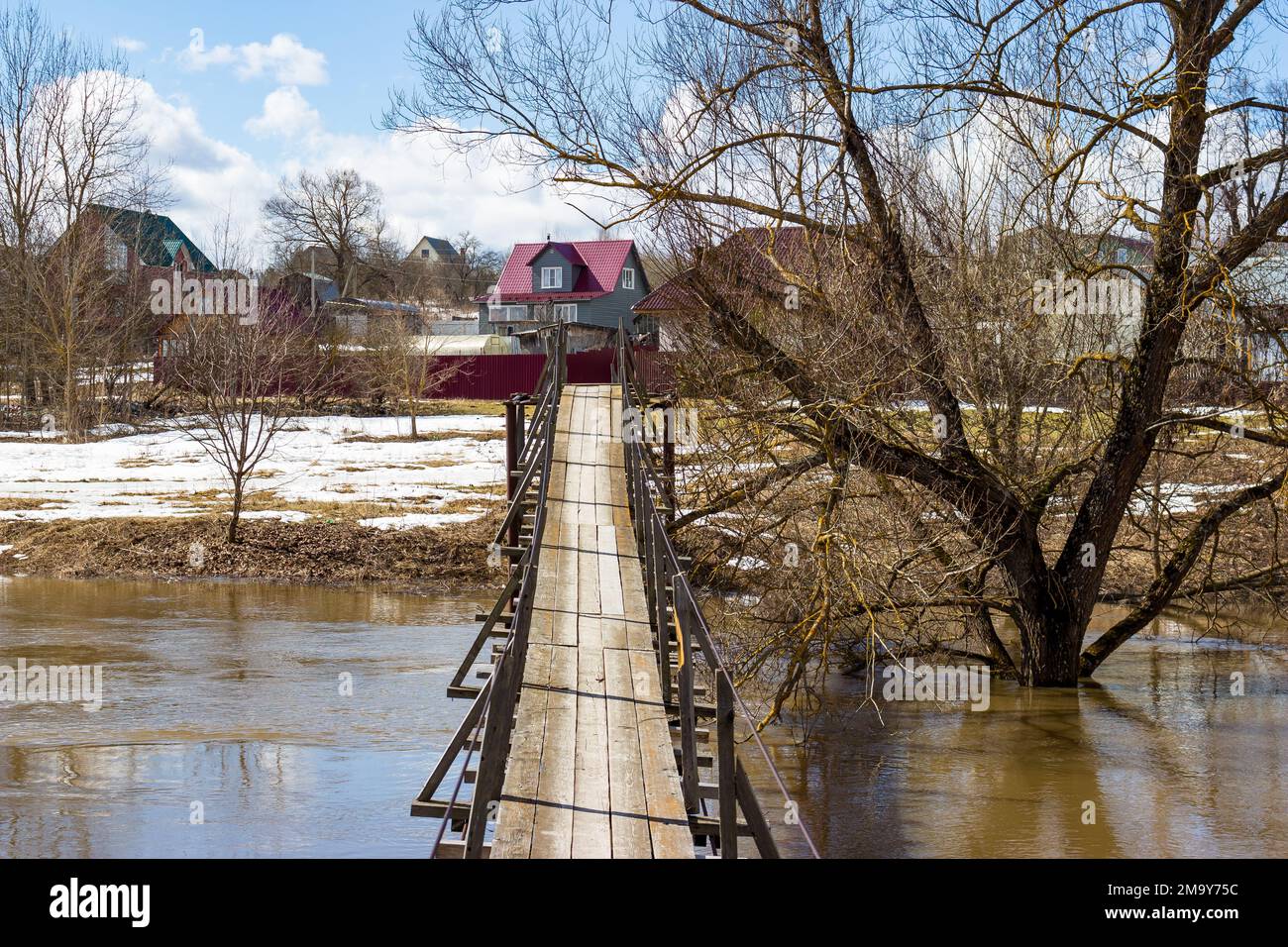 Village footbridge across the river flooded in the spring flood, rural ...