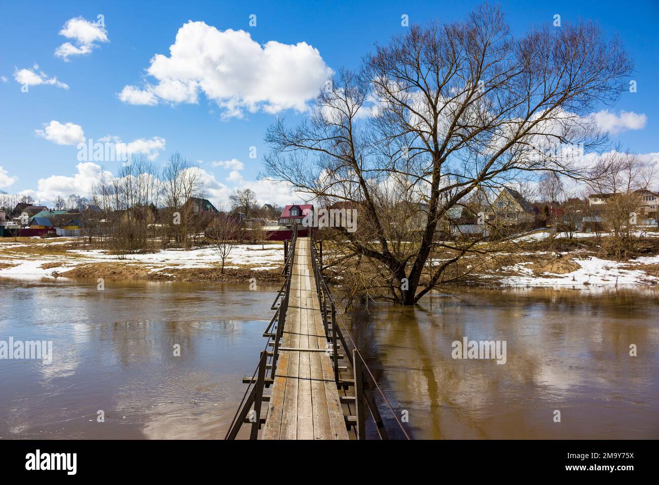 Village footbridge across the river flooded in the spring flood, rural ...