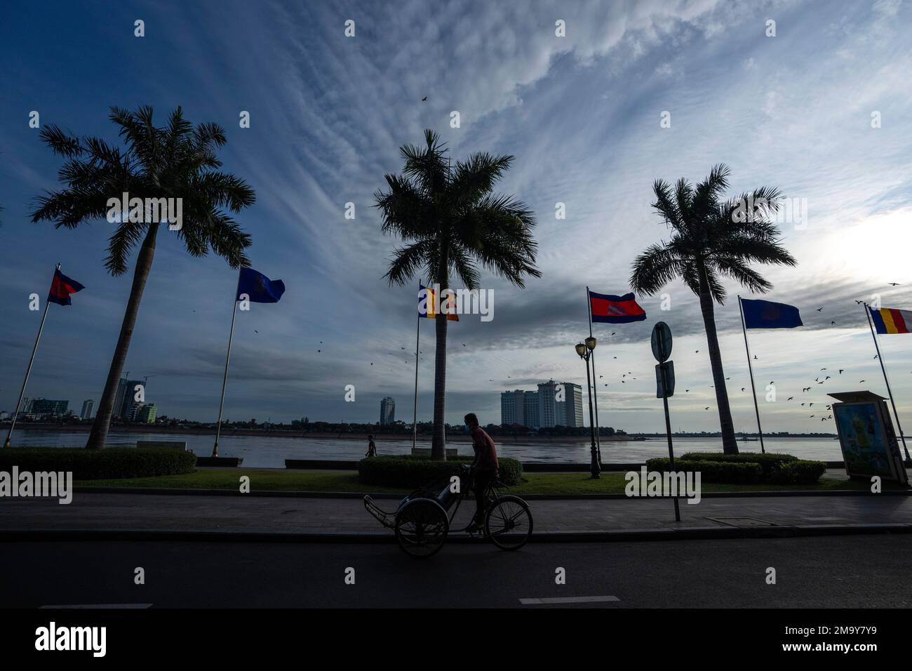A rickshaw puller rides on his rickshaw alongside the Tonle Sap river ...