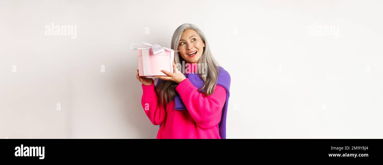 Holidays and valentines day concept. Happy asian mature woman shaking ...