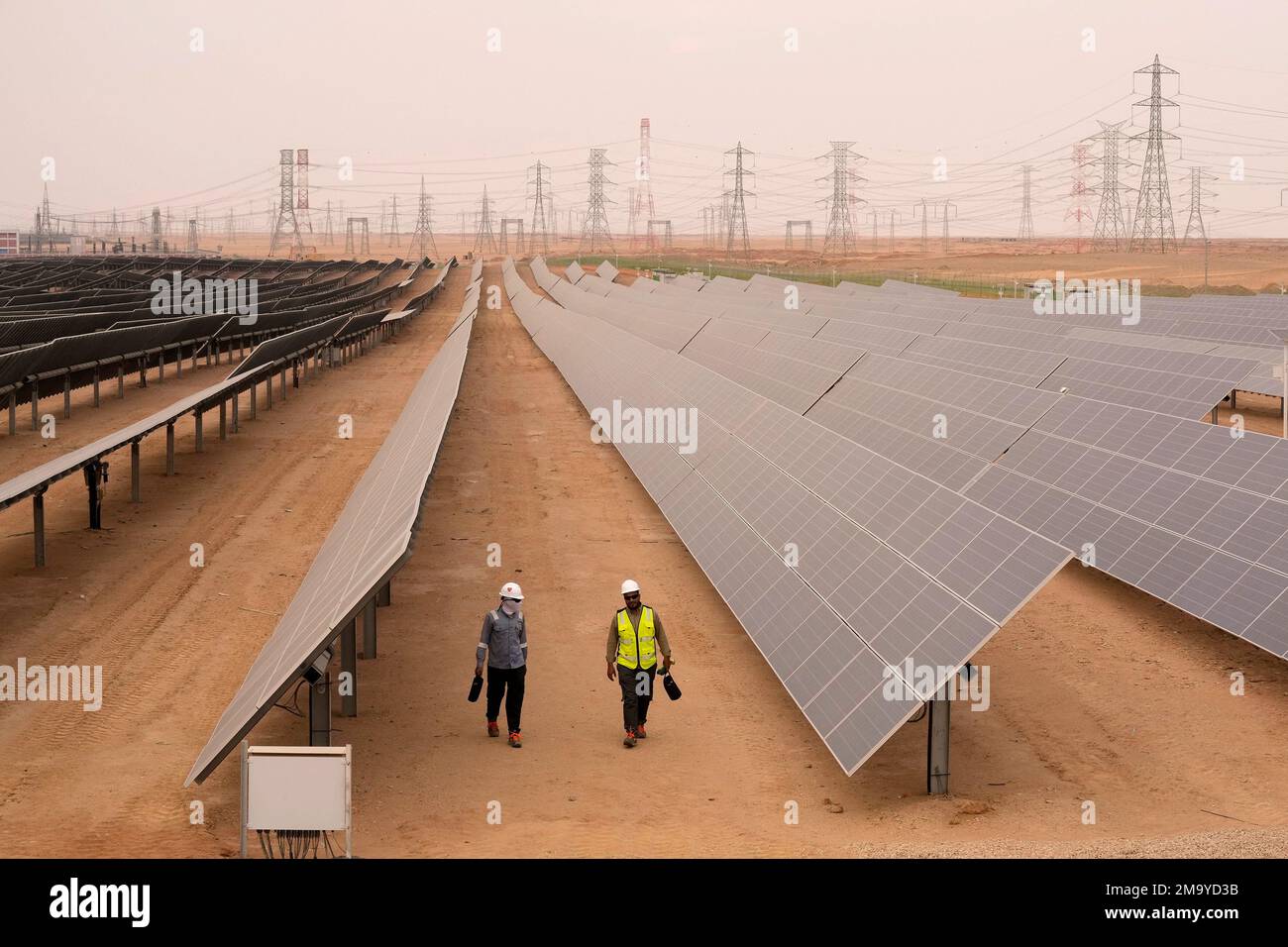 Engineers walk next to solar panels at Benban Solar Park, one of the ...