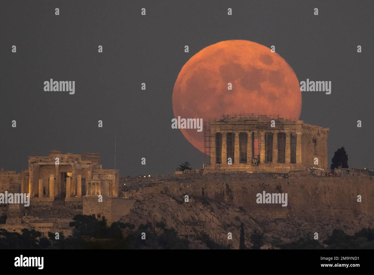 The Full Moon rises behind the Acropolis hill and the ancient Parthenon ...