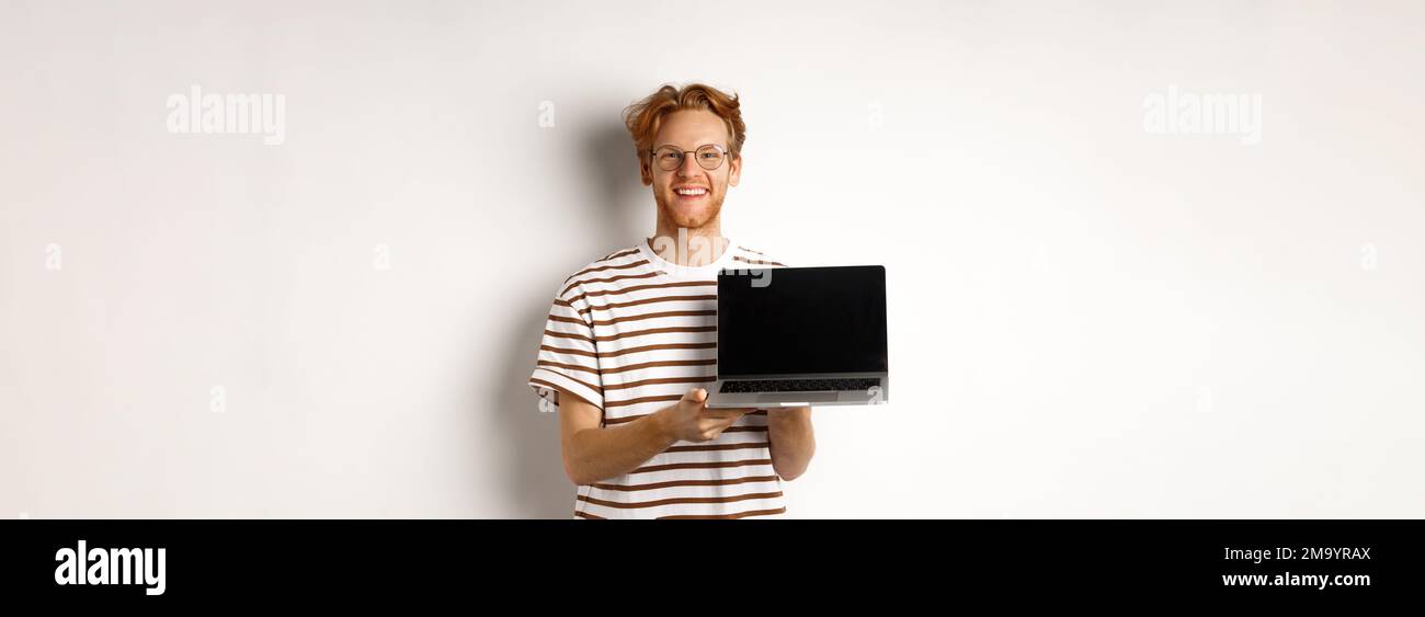 Smiling proud redhead guy showing empty laptop screen. Handsome young ...