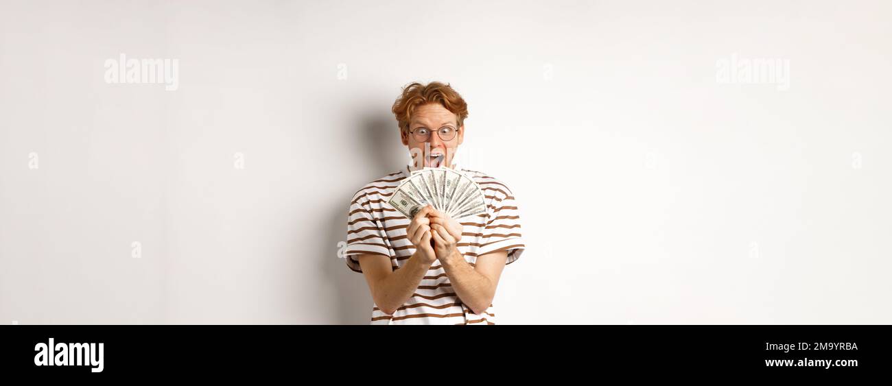 Lucky young man with red hair showing dollars, winning money and ...