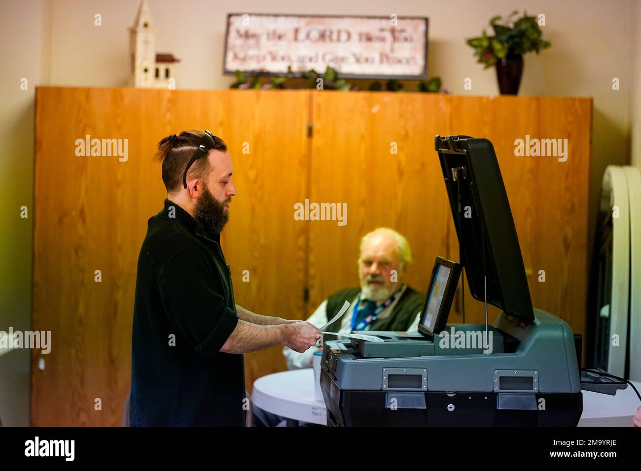 An Ohio voter feeds his paper ballot into the tabulating machine as he ...
