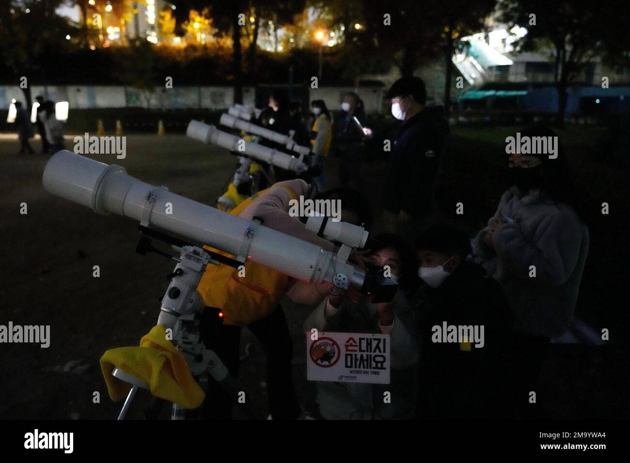 People watch the moon through telescopes during a lunar eclipse in Seoul, South Korea, Tuesday ...