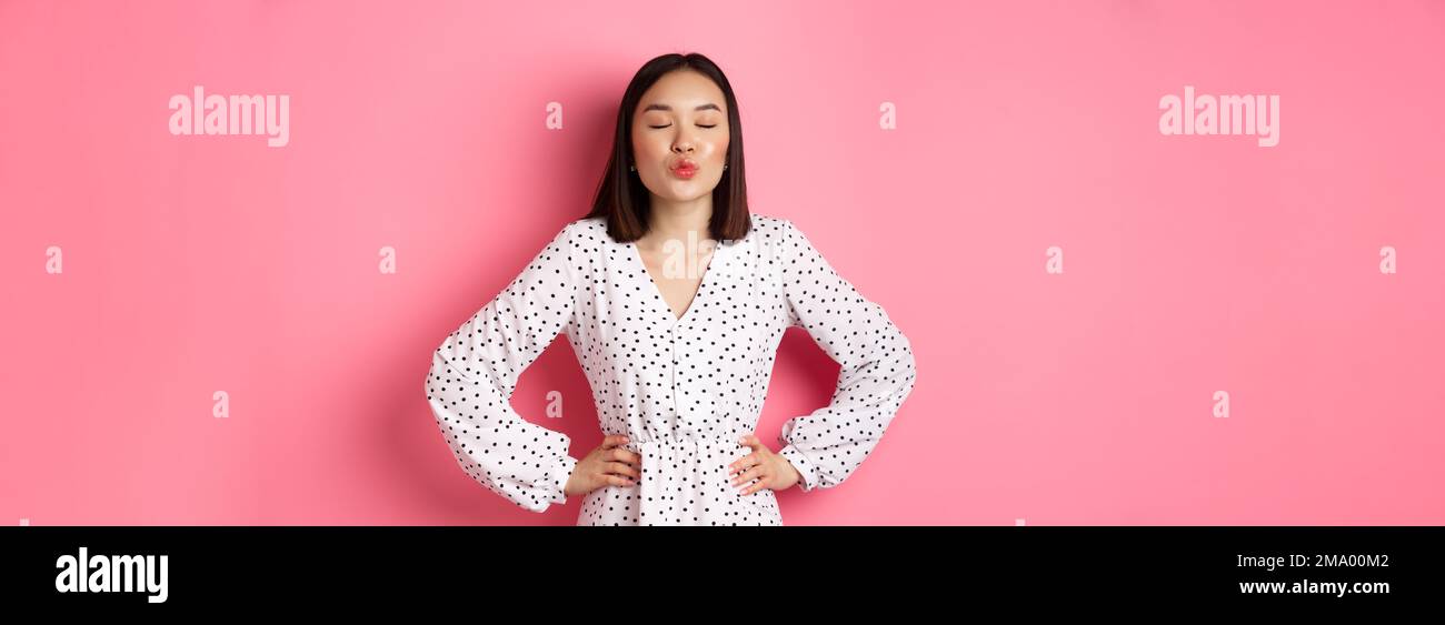 Beautiful asian woman in dress pucker lips and close eyes, waiting for ...