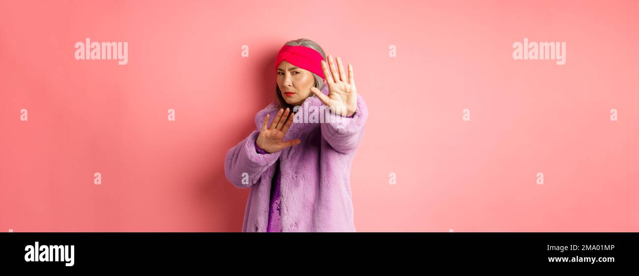 Asian senior female model in stylish purple winter coat standing in ...