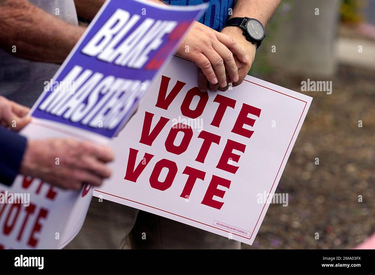 Voters hold signs as they wait to see candidates at a campaign stop ...