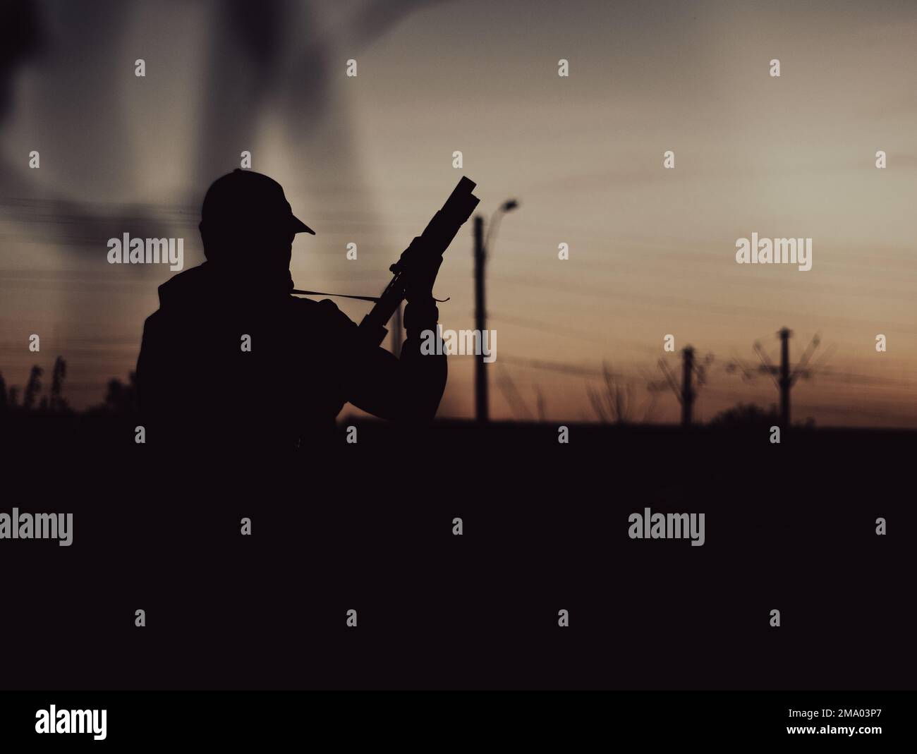 A silhouette of a soldier holding a gun during sunset Stock Photo - Alamy