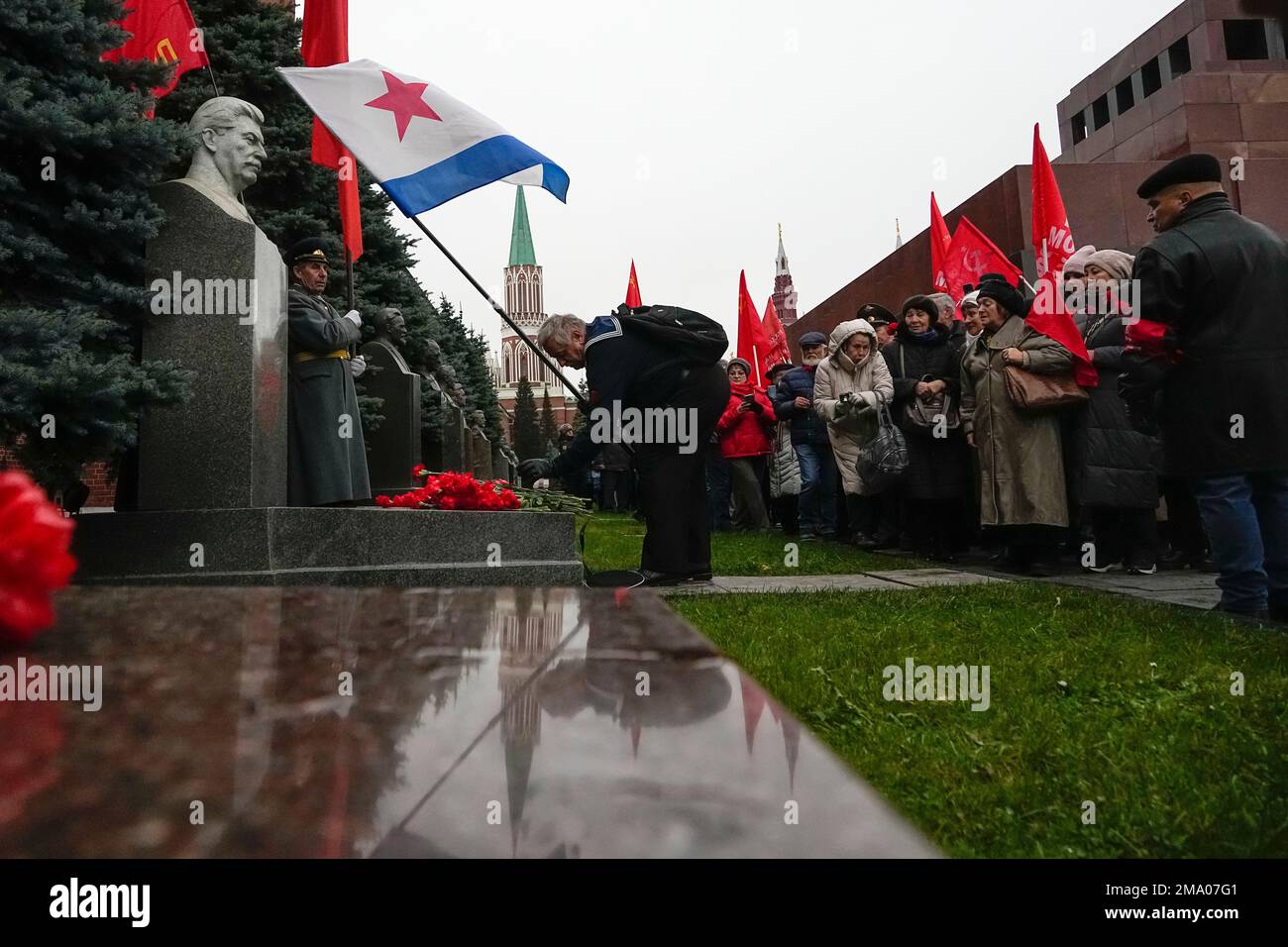 A man with an old Soviet-era navy flag lays flowers at the grave of ...