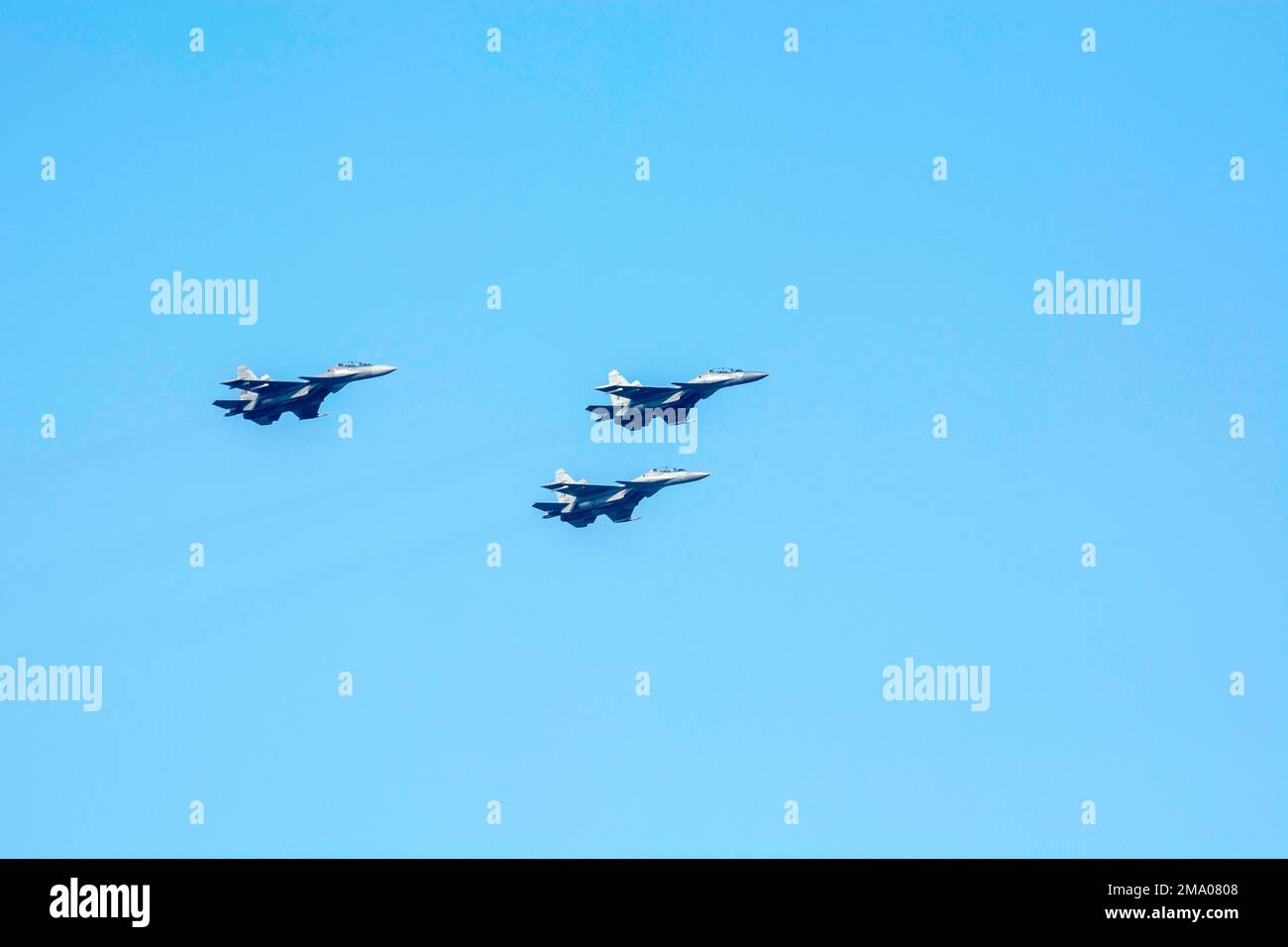 Flying aircraft with Vic formation against isolated blue sky. Three ...