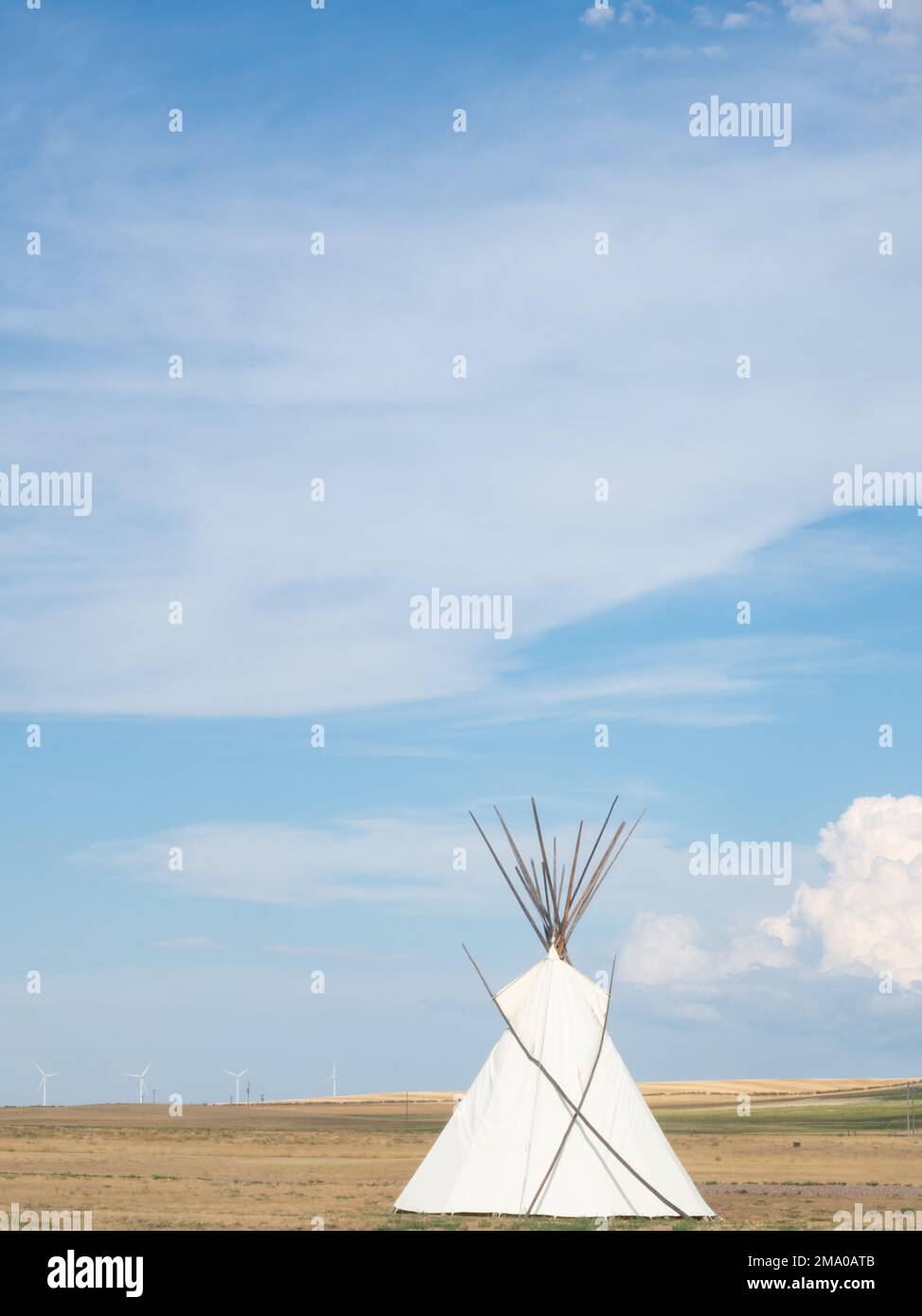 White tipi or teepee in the foreground with wind turbines in the ...