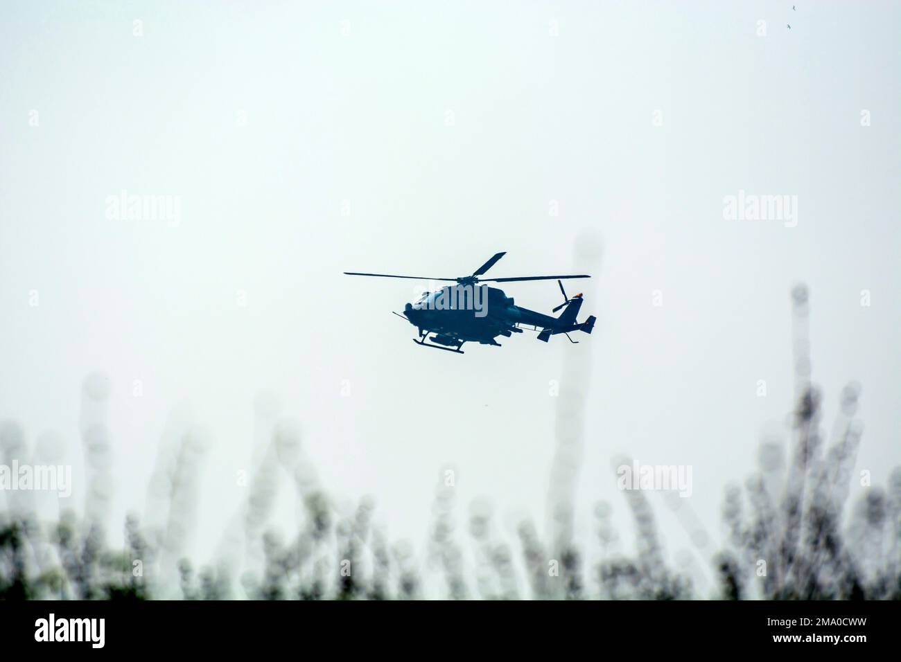 Combat helicopter is flying against isolated blue sky. Combat ...