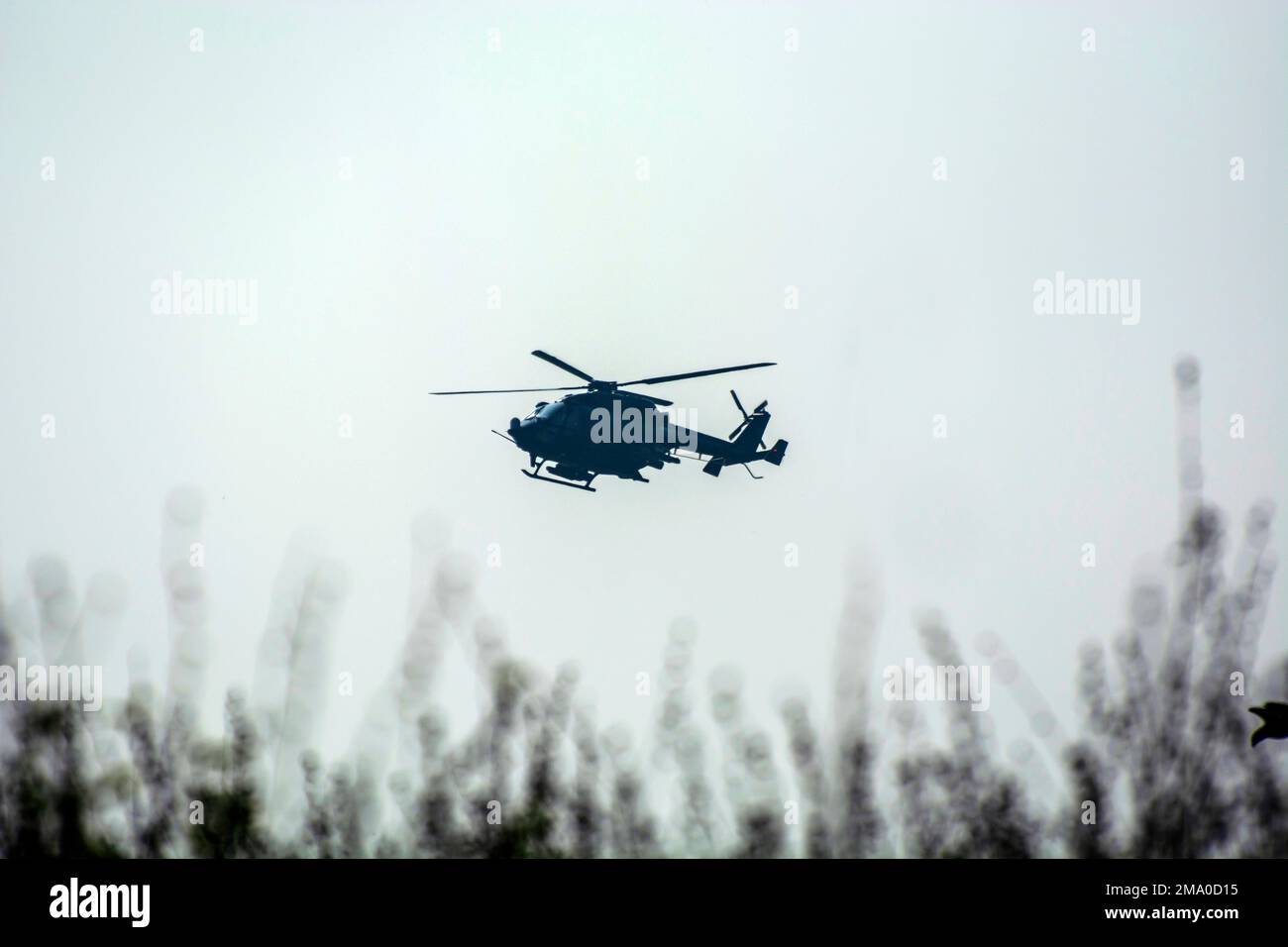 Combat helicopter is flying against isolated blue sky. Combat ...