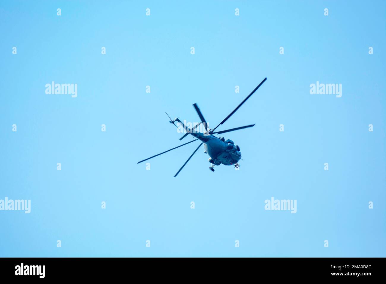 Combat helicopter is flying against isolated blue sky. Combat ...
