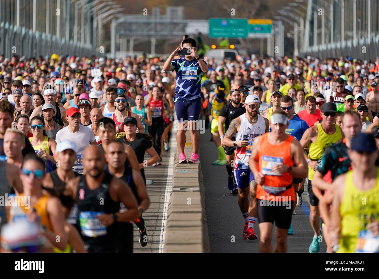 A runner stops to take pictures as the first wave crosses the ...