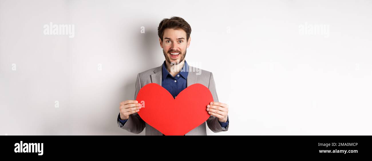 Happy man confessing in love, showing heart cutout and smiling at ...