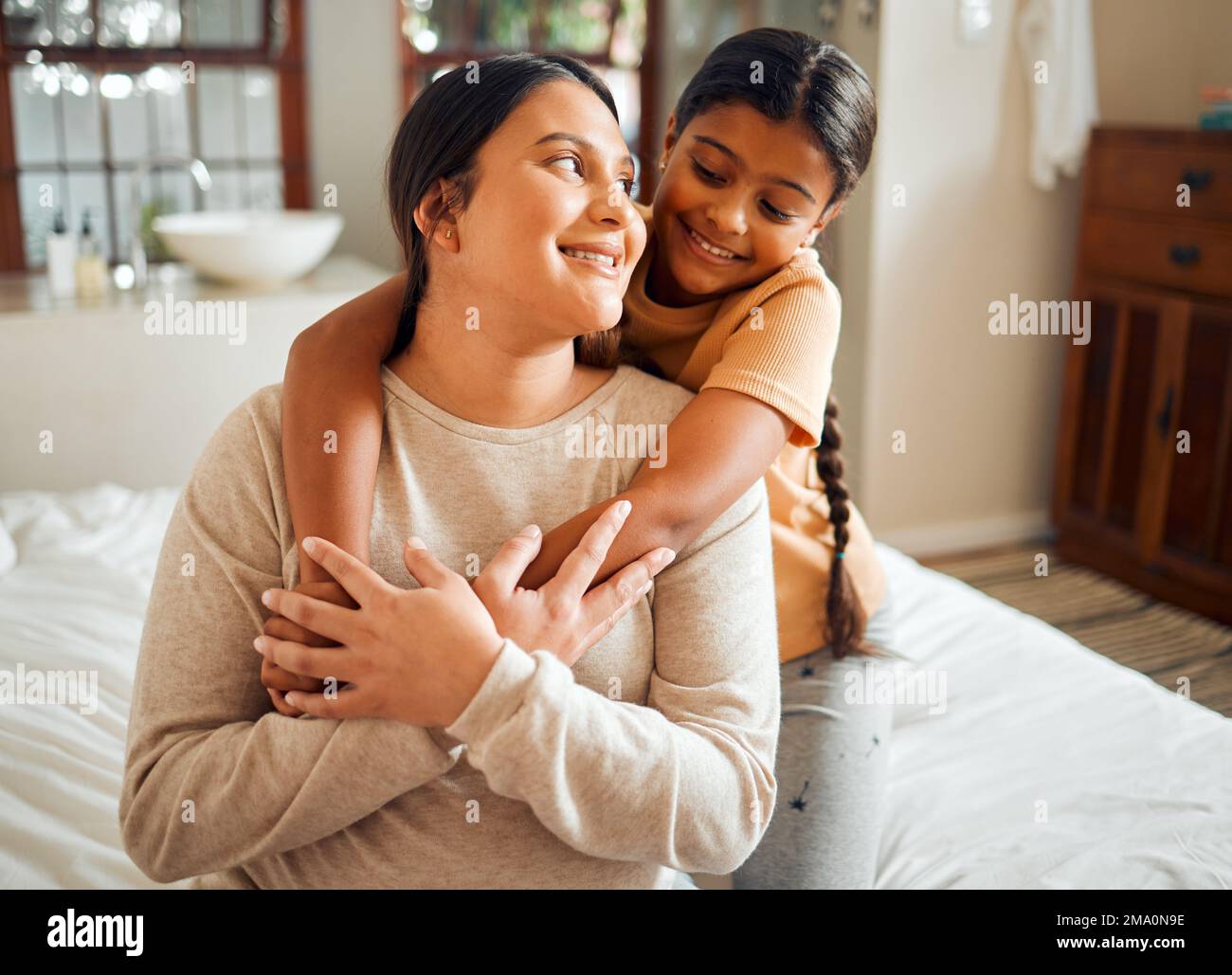 Love, hug and mother and daughter on a bed, bonding and sharing a sweet moment in their home ...