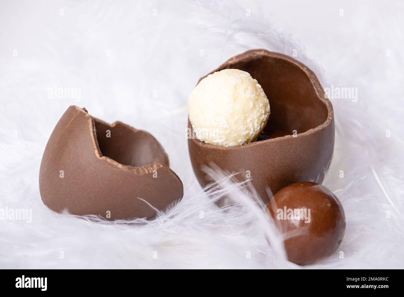 Cracked chocolate easter egg with chocolate small round candies and ...