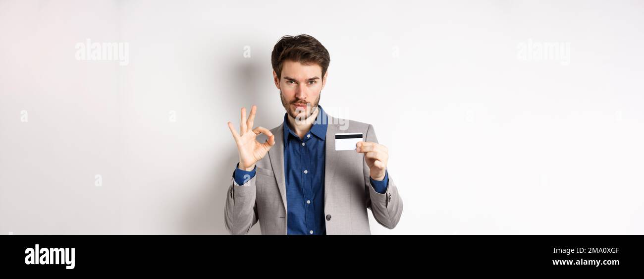 Happy male bank client in business suit showing plastic credit card and ...