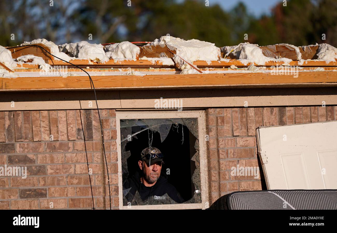 A man looks out of a broken window from a home that was destroyed by a ...