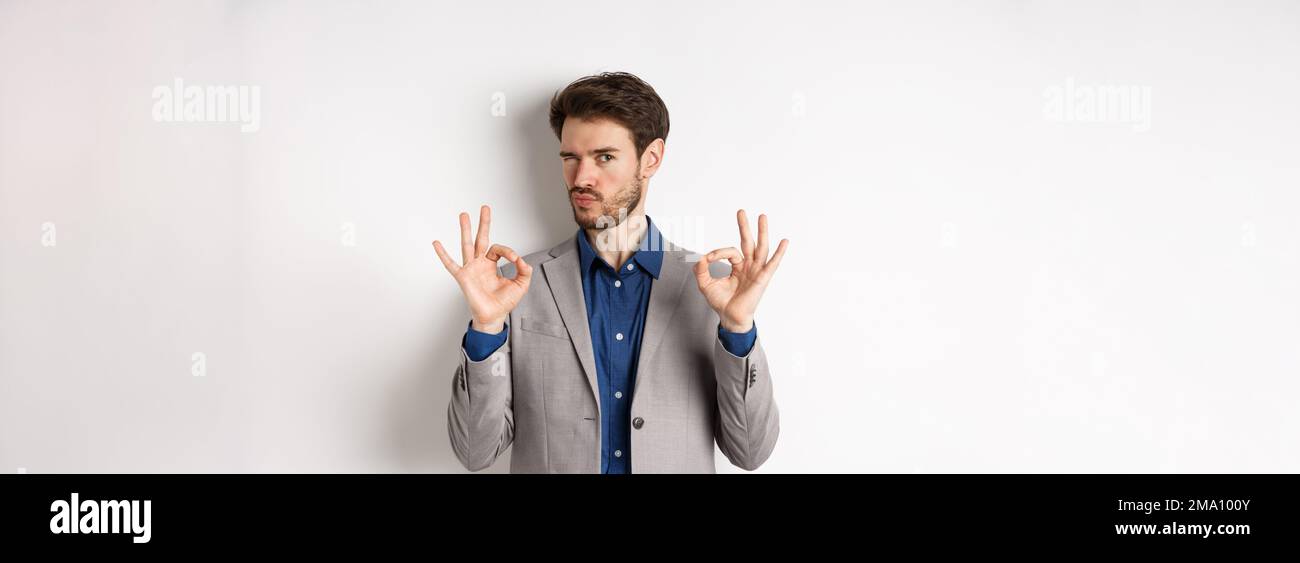 Very good. Handsome stylish guy in suit winking and showing okay sign ...