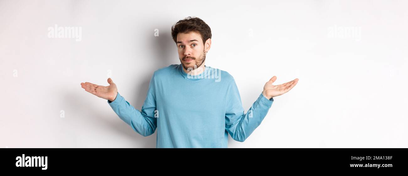 Clueless bearded guy in blue shirt, shrugging shoulders and looking ...