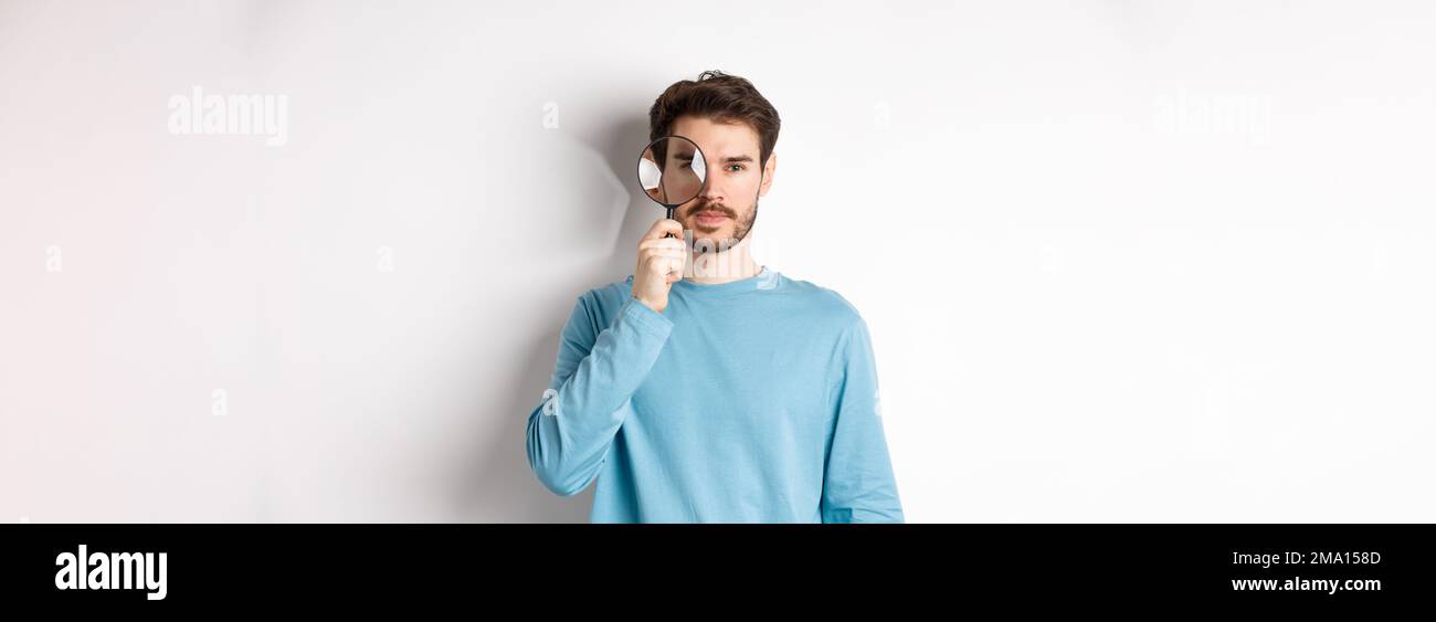 Man searching for something, looking through magnifying glass at camera ...