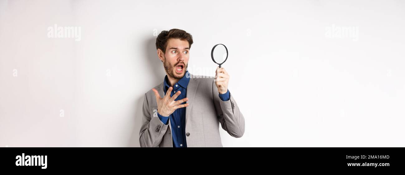 Shocked guy look through mafnifying glass with startled face, gasping ...