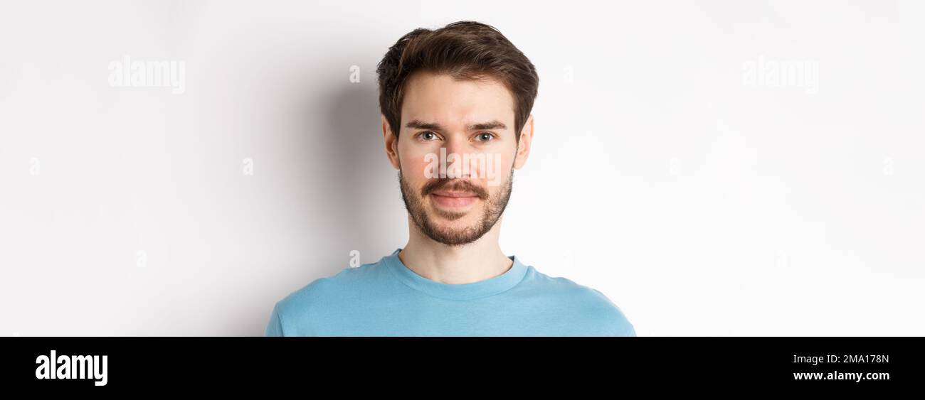 Close up of young handsome man with beard, smiling at camera with ...