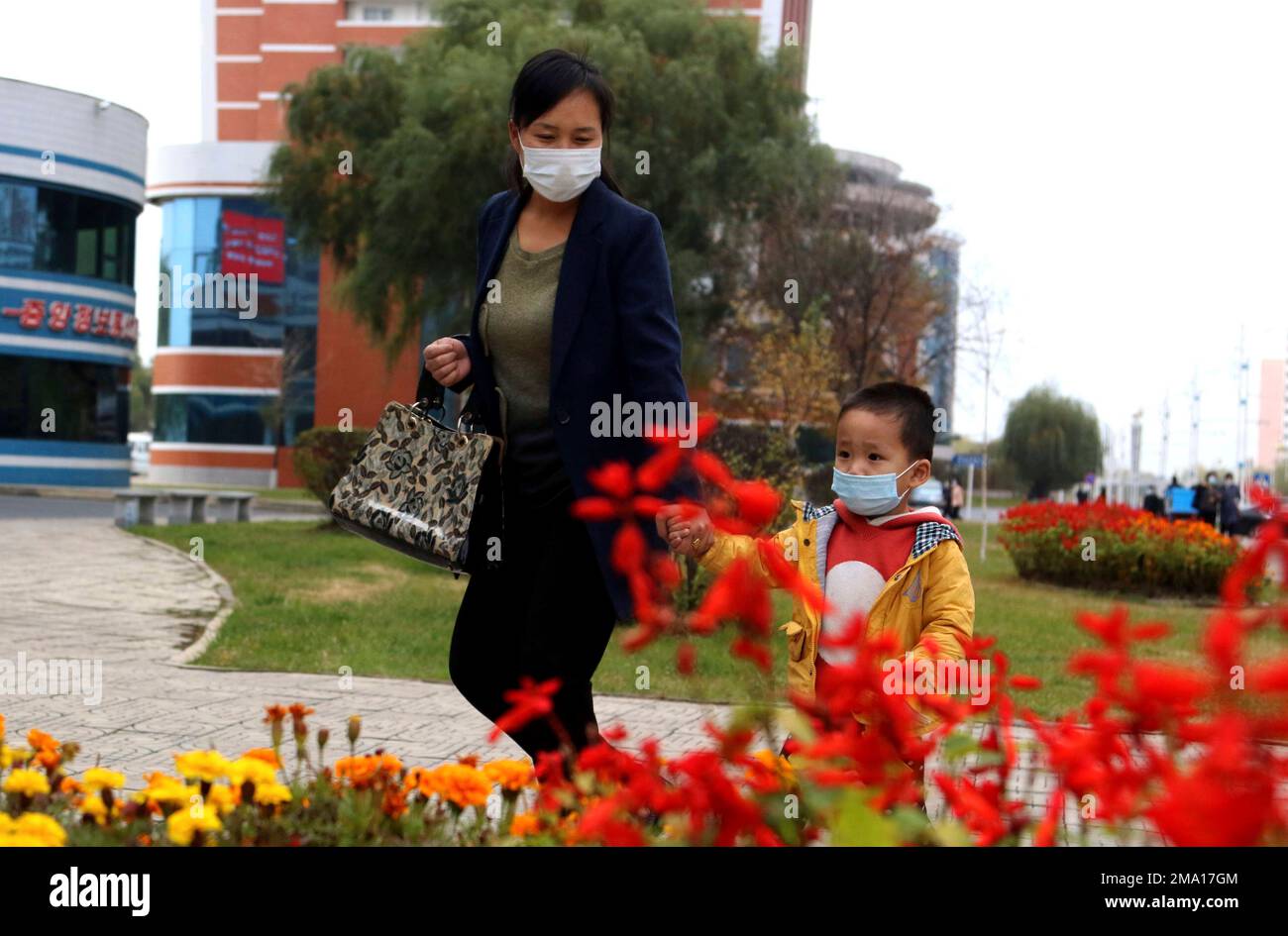 A boy and his mother wearing face masks walk on Mirae Scientists Street ...