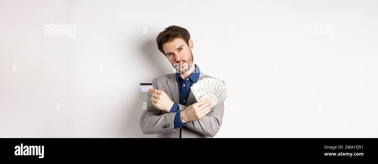 Cool young rich man in suit showing dollar bills and plastic credit ...