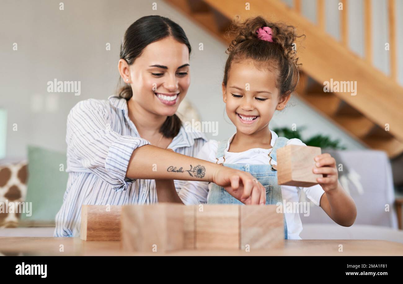 Lets build something cool together. a mother and her daughter playing with wooden blocks ...
