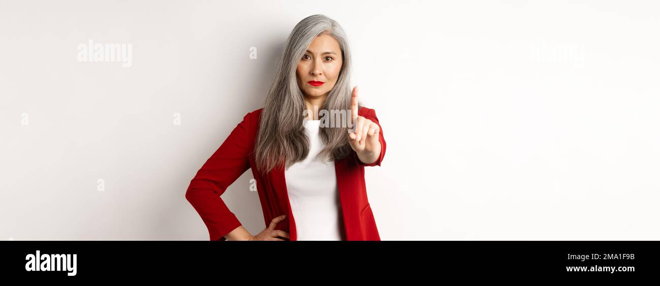 Serious and disappointed asian businesswoman showing stop gesture ...